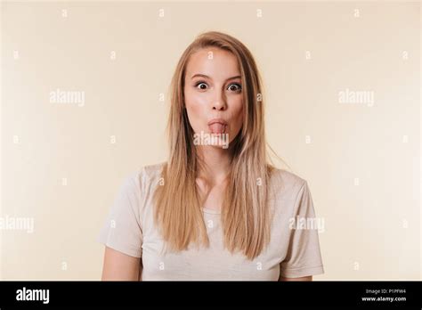 Portrait Of A Funny Casual Girl Sticking Her Tongue Out Isolated Over Beige Background Stock