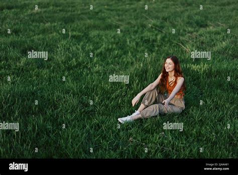 Young Woman Playing Games In The Park On The Green Grass Spreading Her Arms And Legs In