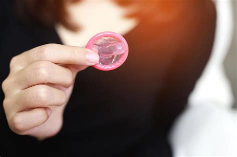 Premium Photo Condom Ready To Use In Female Hand Give Condom Safe Sex Concept On The Bed