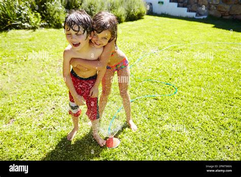 Youre The Best Brother Ever A Brother And Sister Having Fun With A Sprinkler In The Backyard
