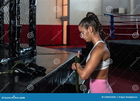 Young Boxer Woman Puts Protective Bandages On Her Hands For Box Training With Boxing Gloves In