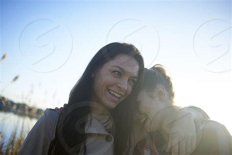 Young Lesbian Couple Lovingly Embracing Each Other In Winter Sunshine Near A Lake By Sash