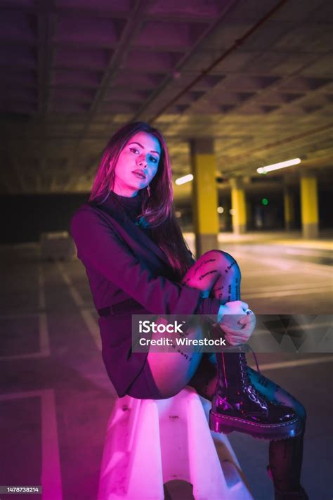Confident Stylish Female Posing Under Colorful Neon Lights In An Underground Car Park Stock