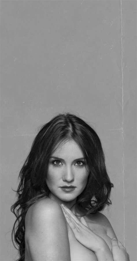 A Black And White Photo Of A Woman With Her Arms Around Her Body Looking At The Camera