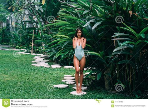 Beautiful Brunette Girl In Blue Swimsuit Posing In Tropical Location With Green Trees Young