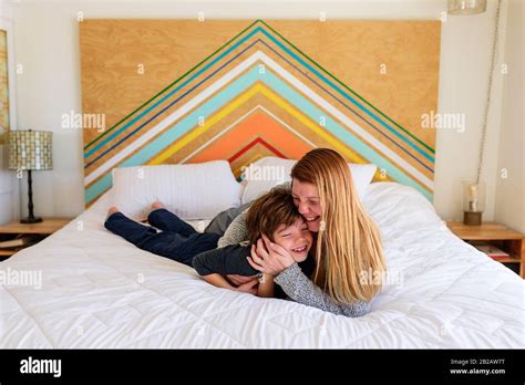 Happy Mother And Son Lying On Bed With Tablet Pc At Home In Bedroom