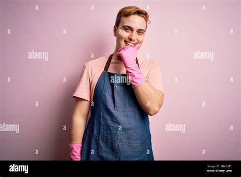 Young Handsome Redhead Cleaner Man Doing Housework Wearing Apron And Gloves Looking Confident At