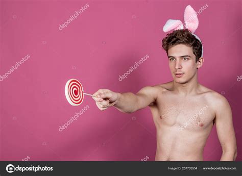 Funny Naked Guy Wearing Bunny Ears Holding Lollipop Over Pink