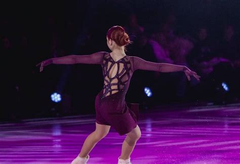 A Woman Skating On An Ice Rink In Front Of A Purple Background With