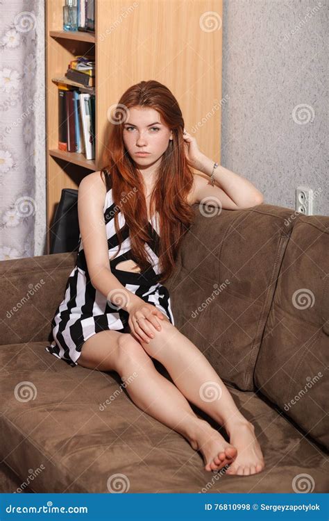 Spontaan Portret Van De Nadenkende Jonge Mooie Zitting Van De Roodharigevrouw Op Achtergrond Van