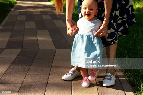 Mom Teaches Daughter To Walk Happy Mom And Daughter Mom With A Oneyearold Daughter In Dresses