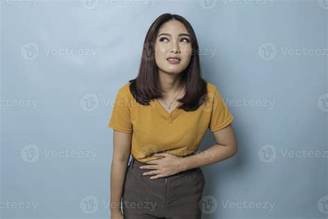 Young Asian Woman With Arms On Stomach And Bending Over With Stomachache Expression 9854928