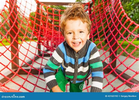 Leuk Het Glimlachen Jong Geitje Op Rood Net Van Speelplaats Stock Foto Image Of Kinderjaren