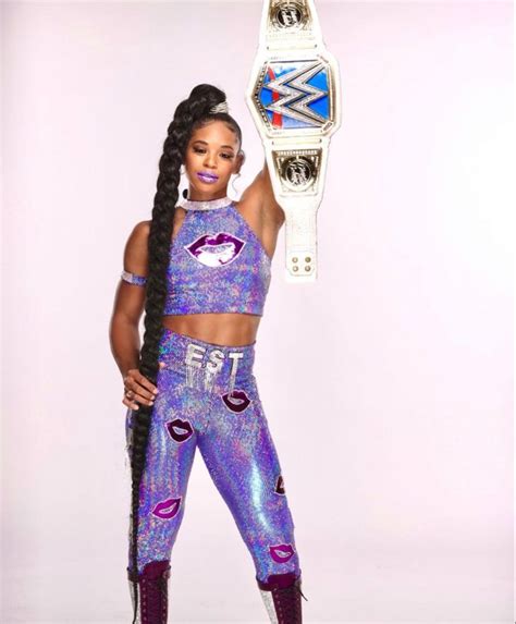 A Woman In Purple And Blue Outfit Holding Up A Wrestling Belt With Her