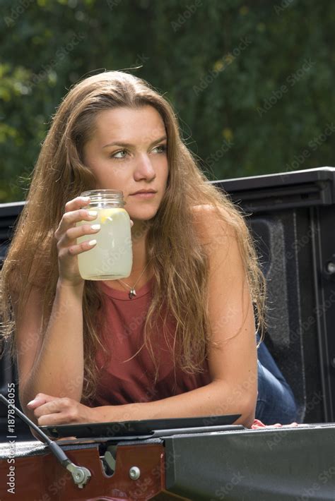 Beautiful Young Country Girl Poses With Jar Of Lemonade In Back Of Pickup Truck On Farm Wearing