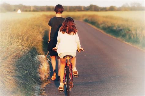 Premium Photo Rear View Of Sister Riding Cycle By Brother Walking On Road