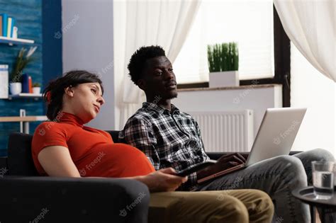 Premium Photo Bored Pregnant Wife Switching Television Programs While Husband Sitting On Sofa