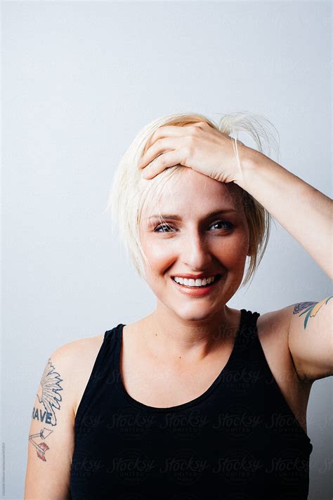 A 32 Year Old Caucasian Woman With Blonde Hair Brushing Her Hair Away From Her Face And Smiling