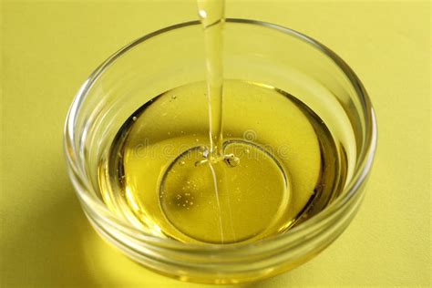 Pouring Cooking Oil Into Bowl On Yellow Background Closeup Stock Image Image Of Gold