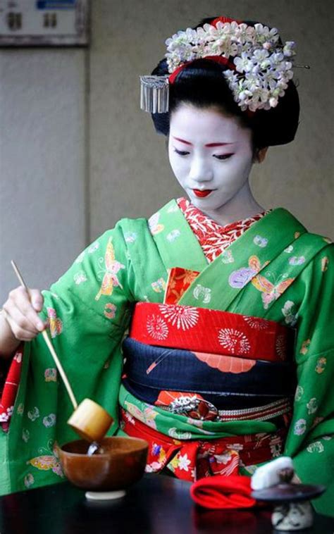A Geisha Woman Dressed In Traditional Japanese Clothing With Chopsticks And Bowl Of Food