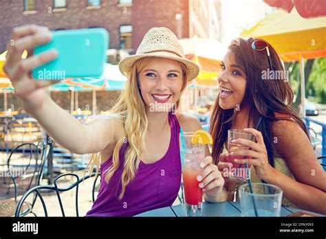Selfies With My Bestie Two Attractive Young Women Taking A Selfie While Sitting At An Outdoor