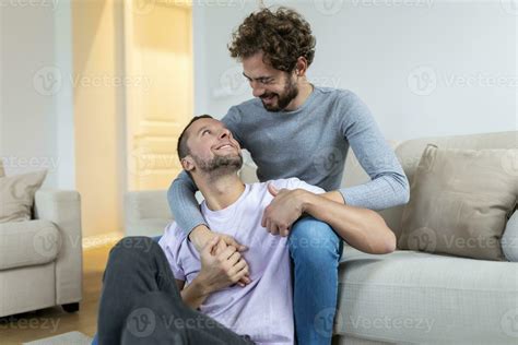 Lovely Gay Couple Kissing While Sitting In Their Living Room At Home Two Romantic Young Male