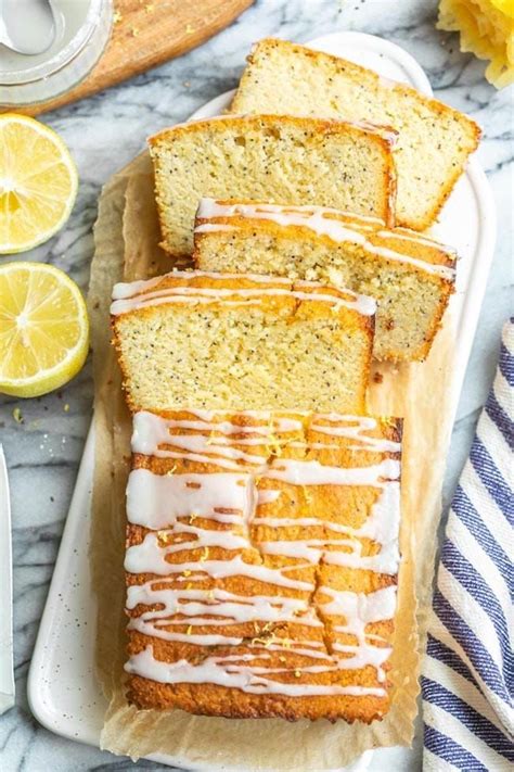 Sliced Lemon Loaf With White Icing On A Plate Next To Slices Of Lemons