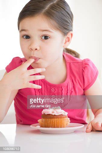 Mixed Race Girl Licking Frosting From Finger Foto Stock Getty Images