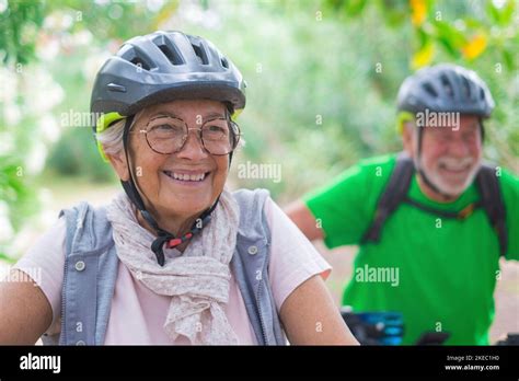 Portrait Of One Old Woman Smiling And Enjoying Nature Outdoors Riding Bike With Her Husband