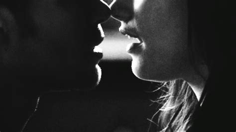 A Man And Woman Kissing Each Other In Black And White