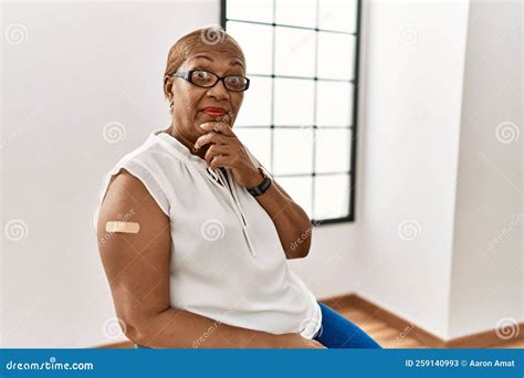 Mature Hispanic Woman Getting Vaccine Showing Arm With Band Aid Thinking Worried About A
