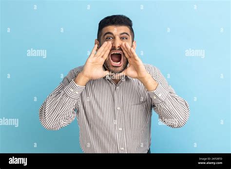 Portrait Of Handsome Crazy Businessman With Beard Loudly Screaming Holding Hand Near Widely