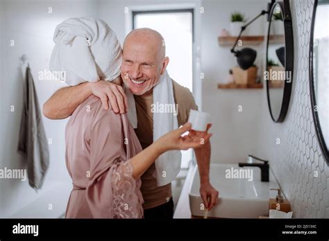 Senior Couple In Love In Bathroom Brushing Teeth And Hugging Morning Routine Concept Stock