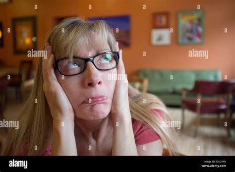 Female Wearing Glasses Pulling Cheeks Back Sticking Bottom Lip Out And Looking Upward Stock