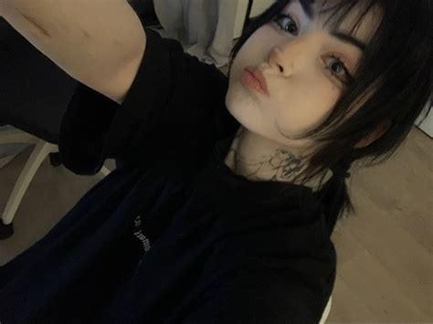 A Woman With Black Hair And Piercings On Her Face Is Taking A Selfie