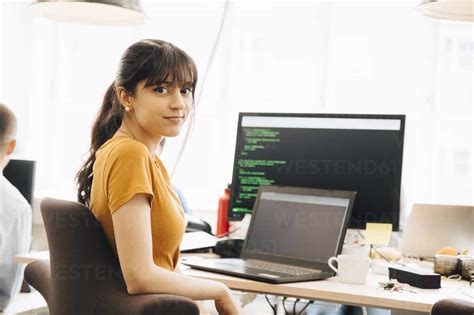 Portrait Of Female Programmer Using Laptop While Sitting At Desk In