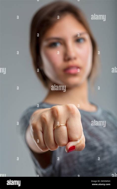 In The Foreground A Fist Forward From The Extended Arm Of A Young Girl In The Blurred Background