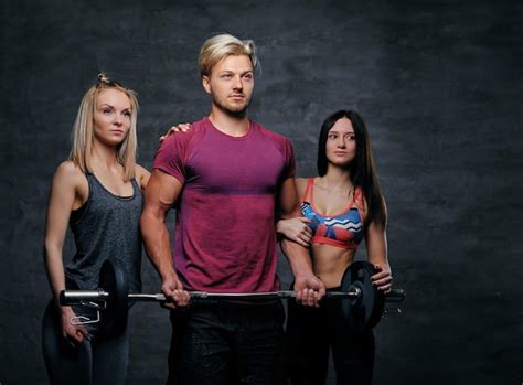 Premium Photo Threesome Fitness Model Of Blond And Brunette Slim Women And A Man Holds Barbell